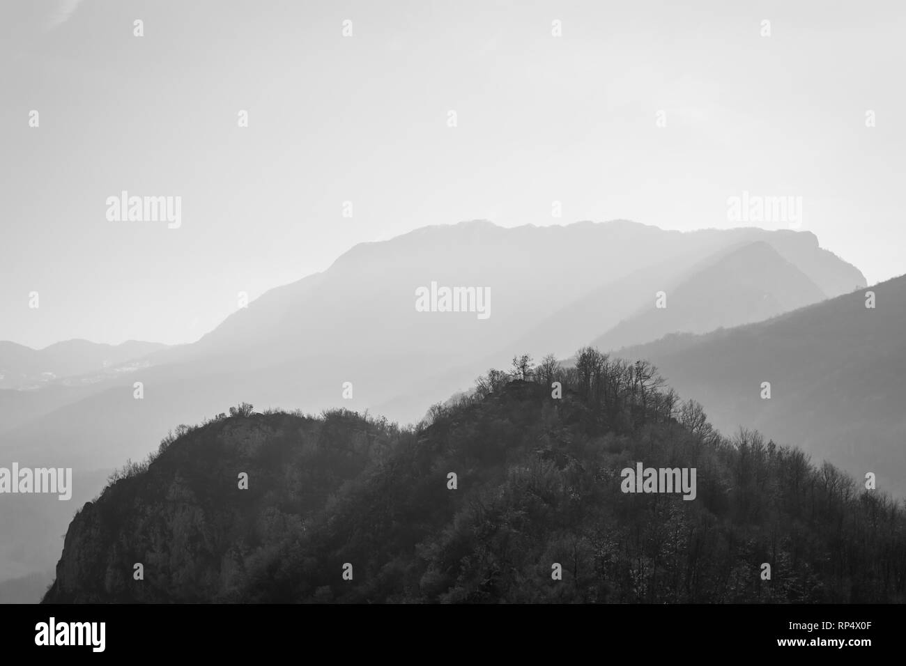 Soft, hazy, black and white view of impressive rocky mountain summit ...
