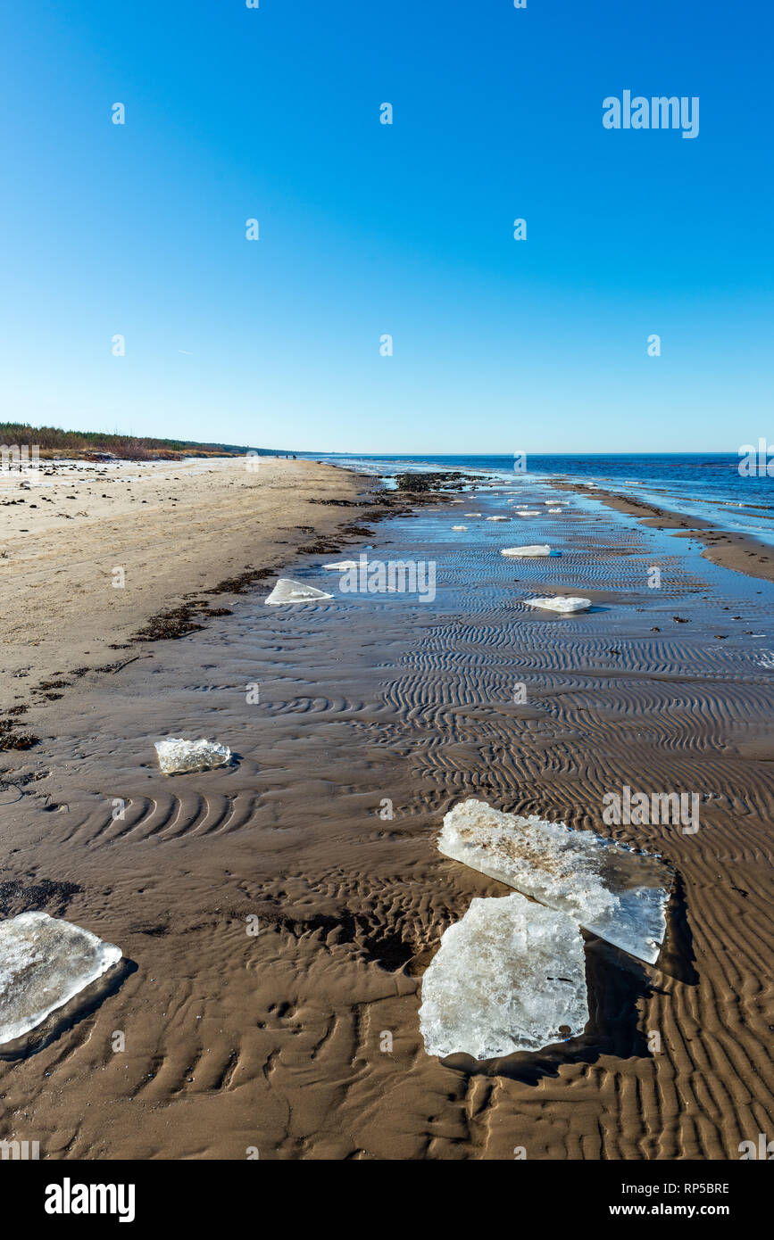 frozen ice blocks on sea beach in winter with sand and snow in overcast ...