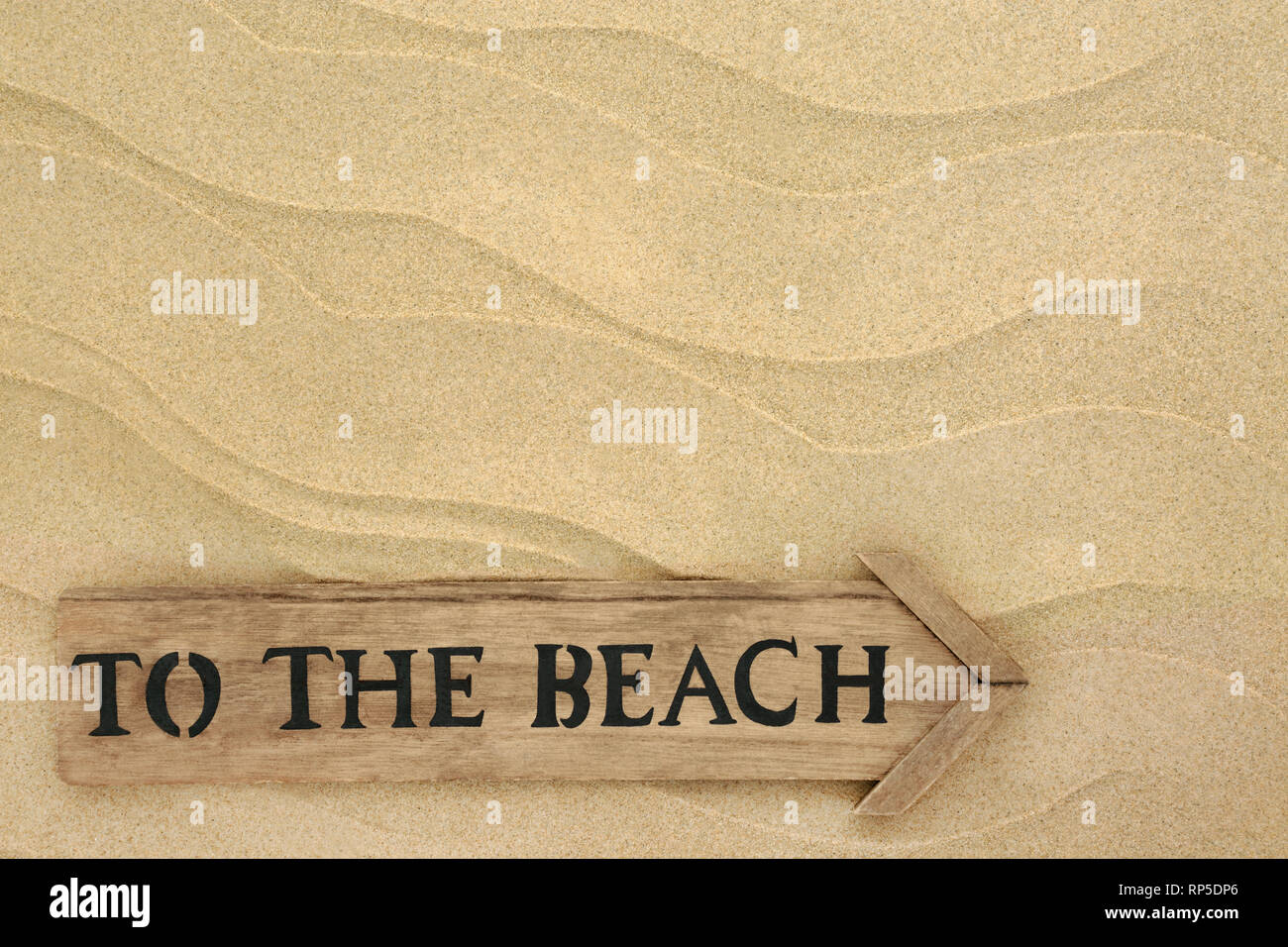 Rustic wooden to the beach sign on sand with wave lines. Top view with ...