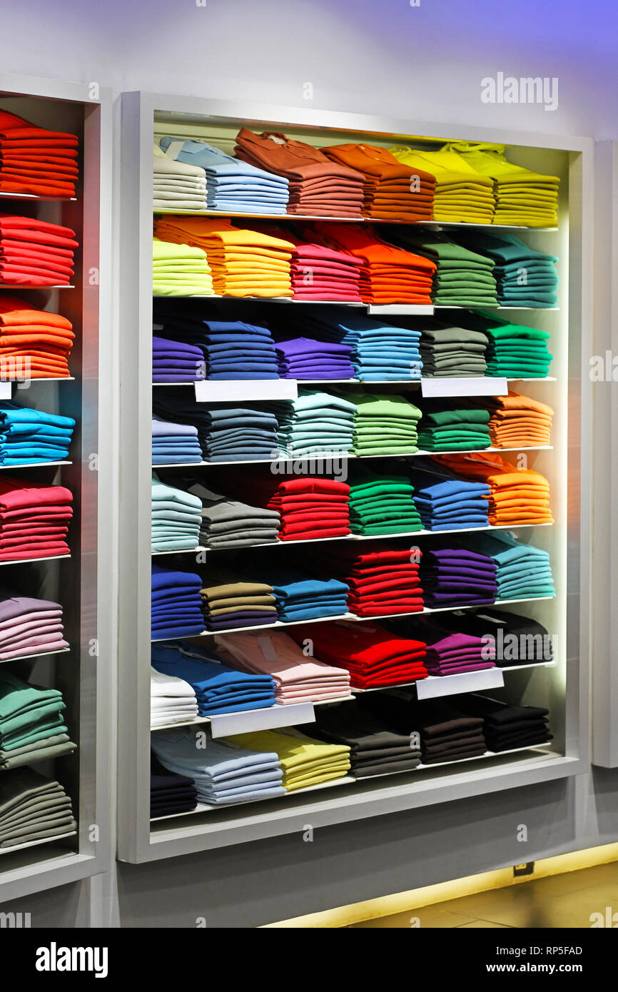 Various colour shirts at shelf in shop Stock Photo - Alamy