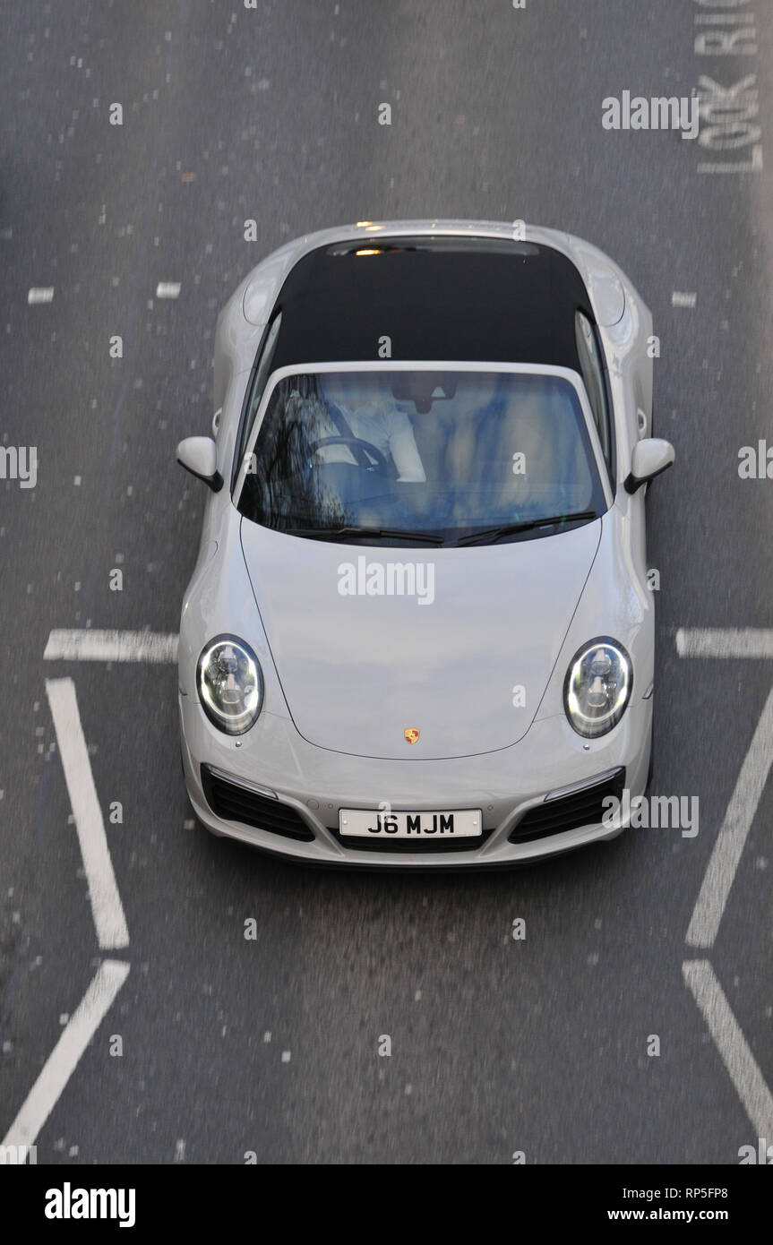 A silver Porsche 911 convertible photographed from above as it drives ...