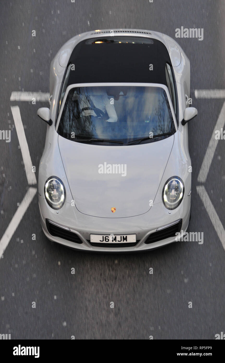 A silver Porsche 911 convertible photographed from above as it drives ...