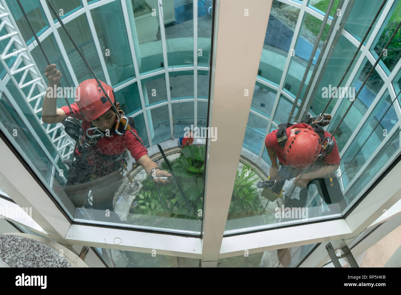 Workers in safety gear perform high-rise window cleaning on a glass ...