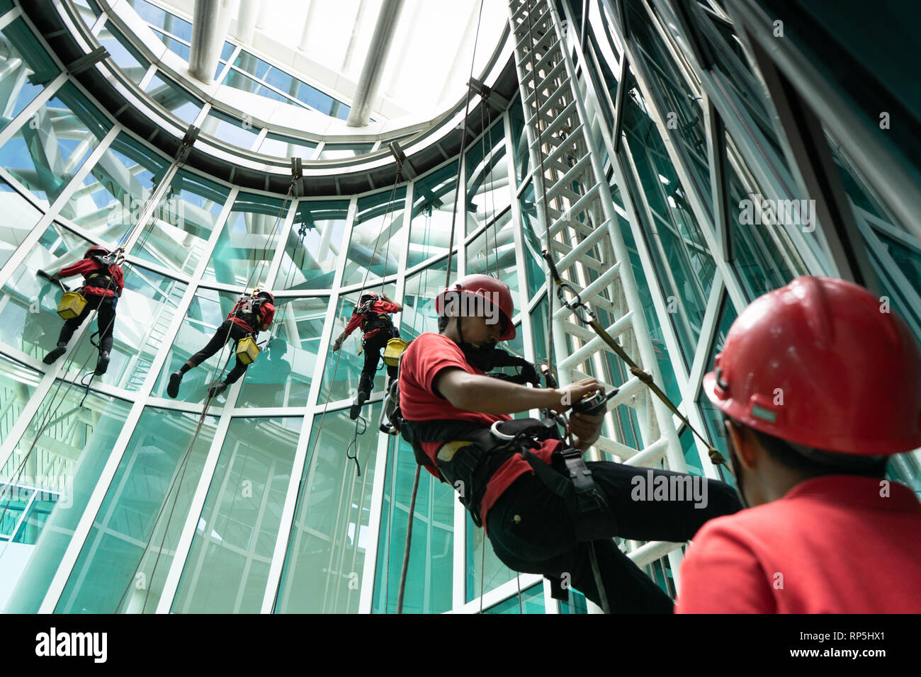 Workers in safety gear perform high-rise window cleaning on a glass ...