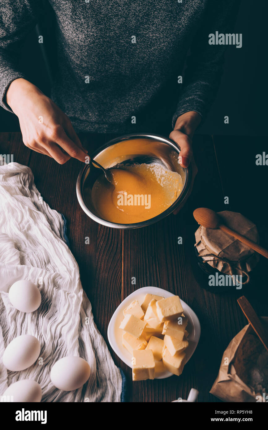 Process of cooking dough for pie. View from above female's hands mixing ...