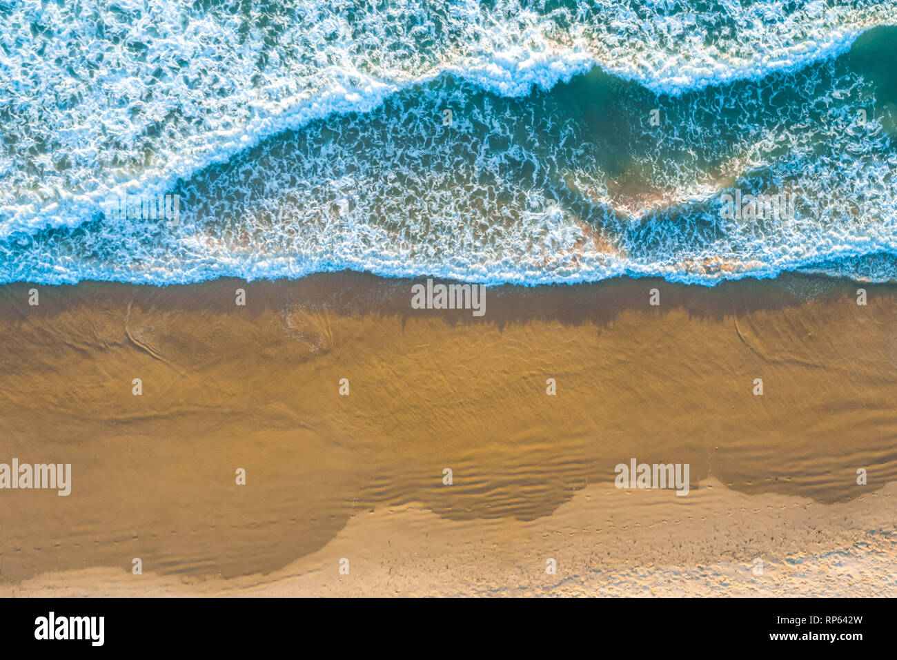 Ocean waves crash into the shore at sunset - aerial view with copy space Stock Photo - Alamy