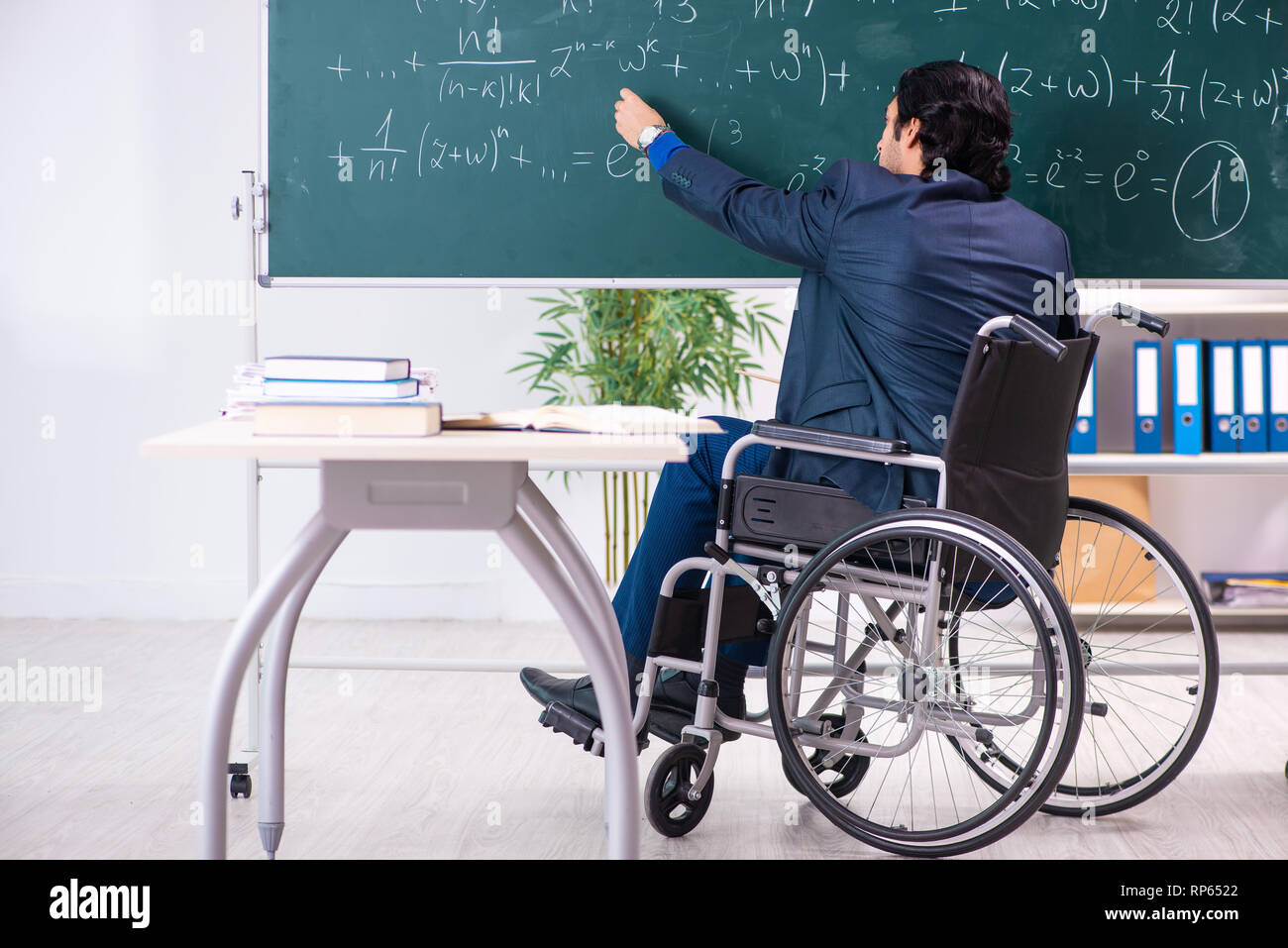 Young handsome man in wheelchair in front of chalkboard Stock Photo - Alamy
