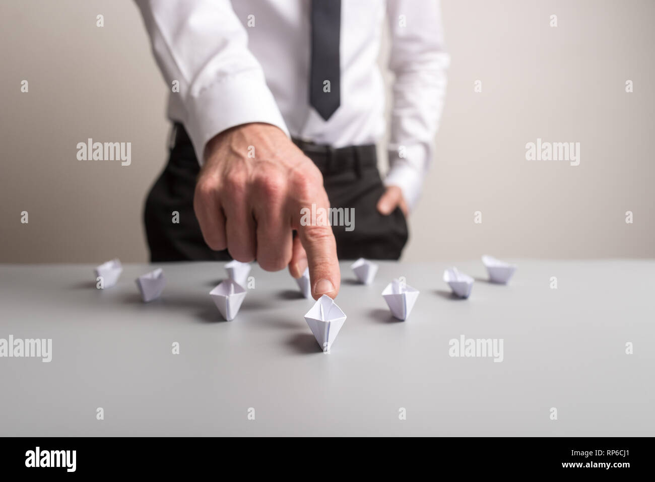 Businessman pushing forward the leading paper made boat in an arrow ...