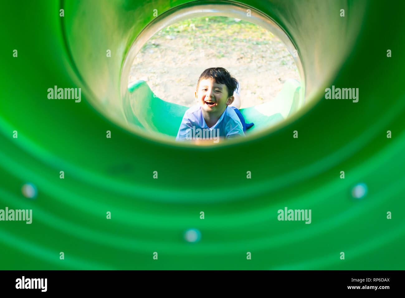 Little Asian kid climbing up the slide at the playground under the ...