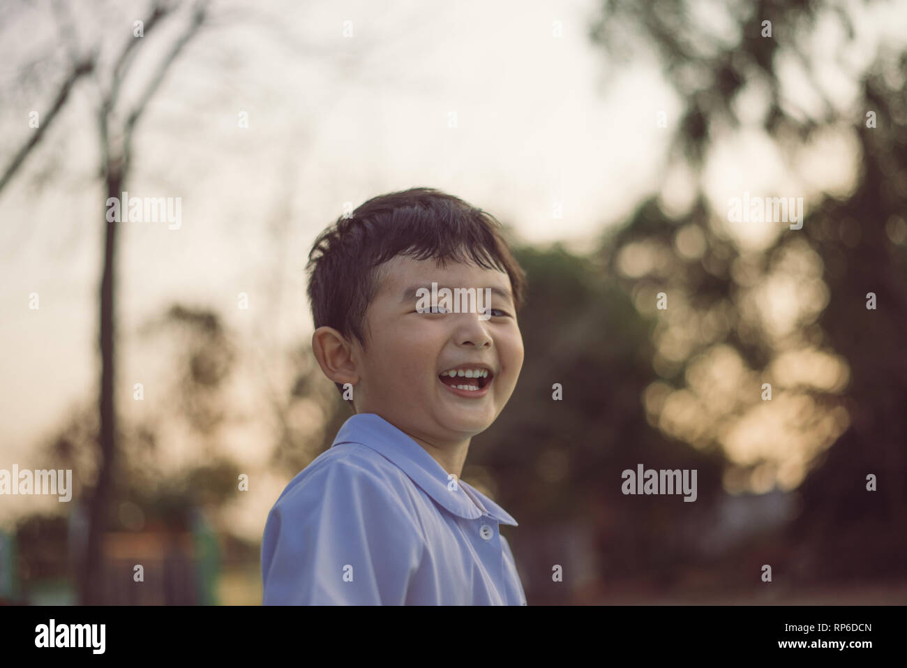 Outdoor portrait of a happy Asian student kid in school uniform smiling ...