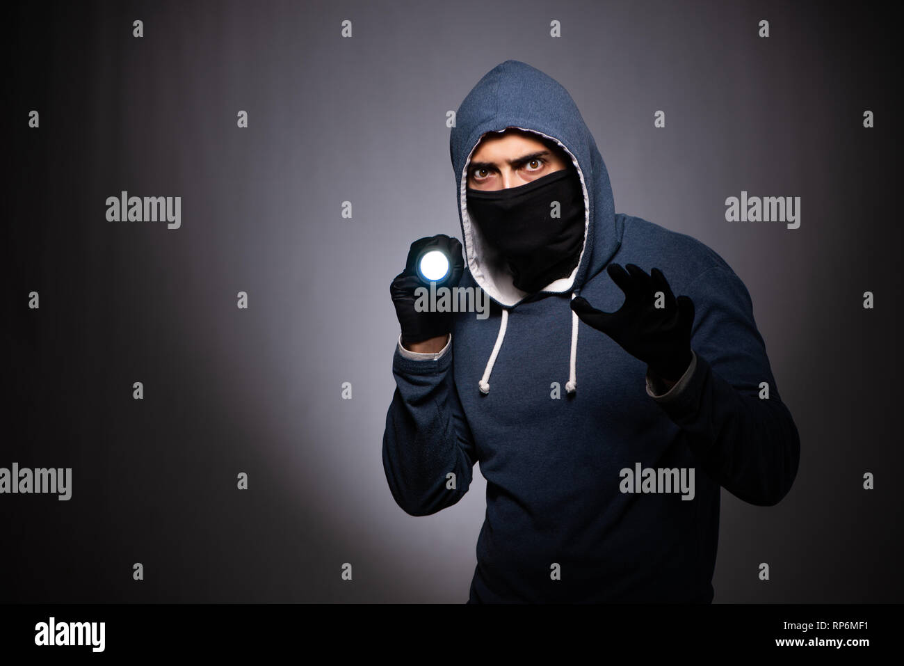 Young gangster in hood on grey background Stock Photo - Alamy