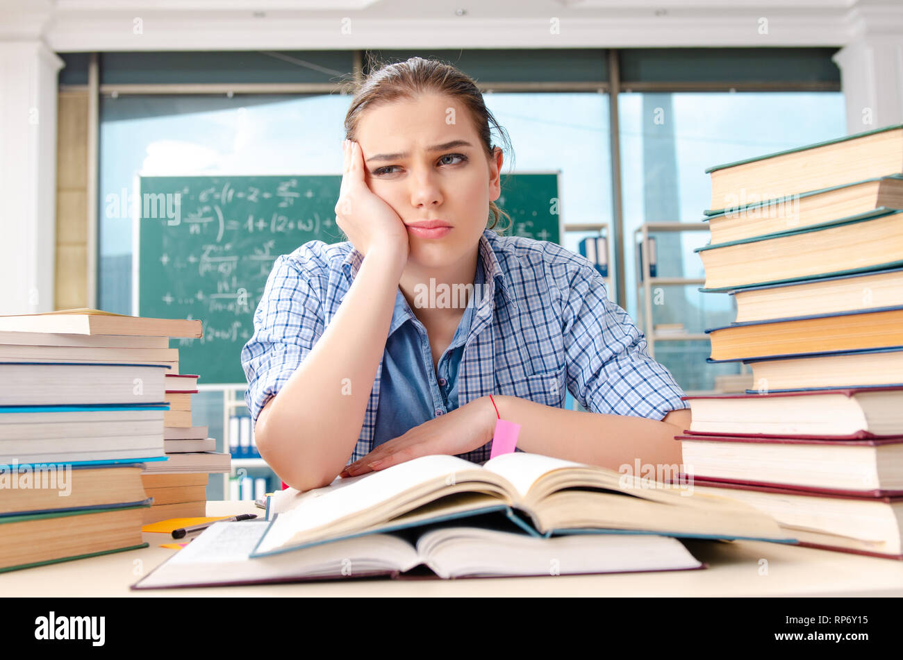 Female student with many books sitting in the classroom Stock Photo - Alamy