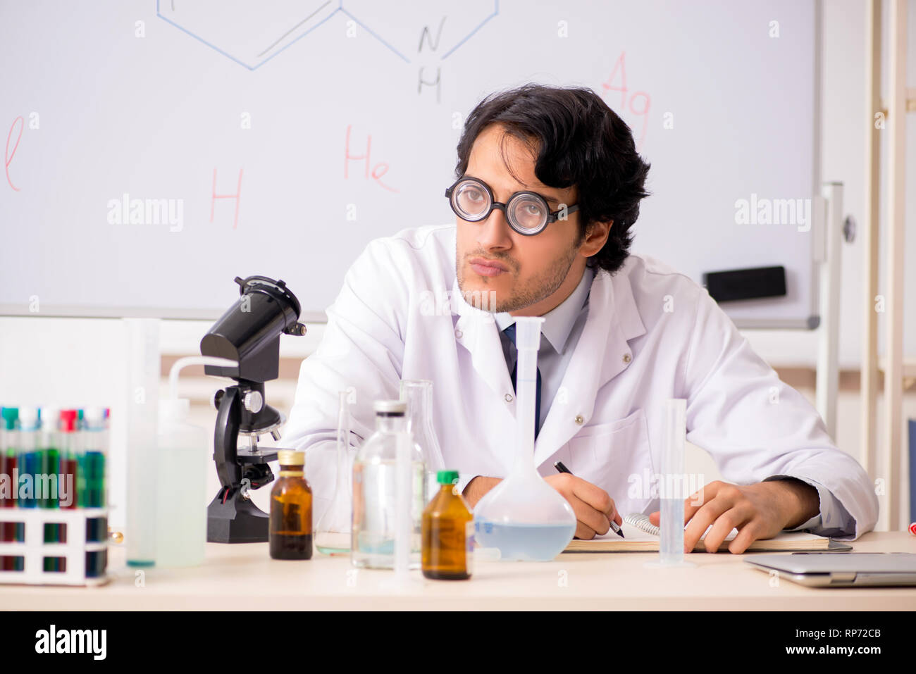 Young funny chemist in front of white board Stock Photo - Alamy