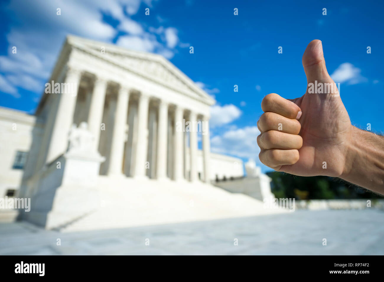 An optimistic hand sticks a thumb up in approval in front of the United ...