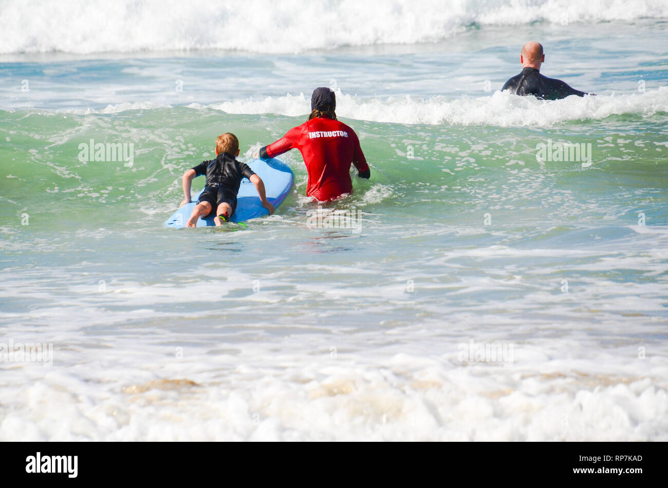 Young boy help through shore break during surf lesson. Boy discovers ...