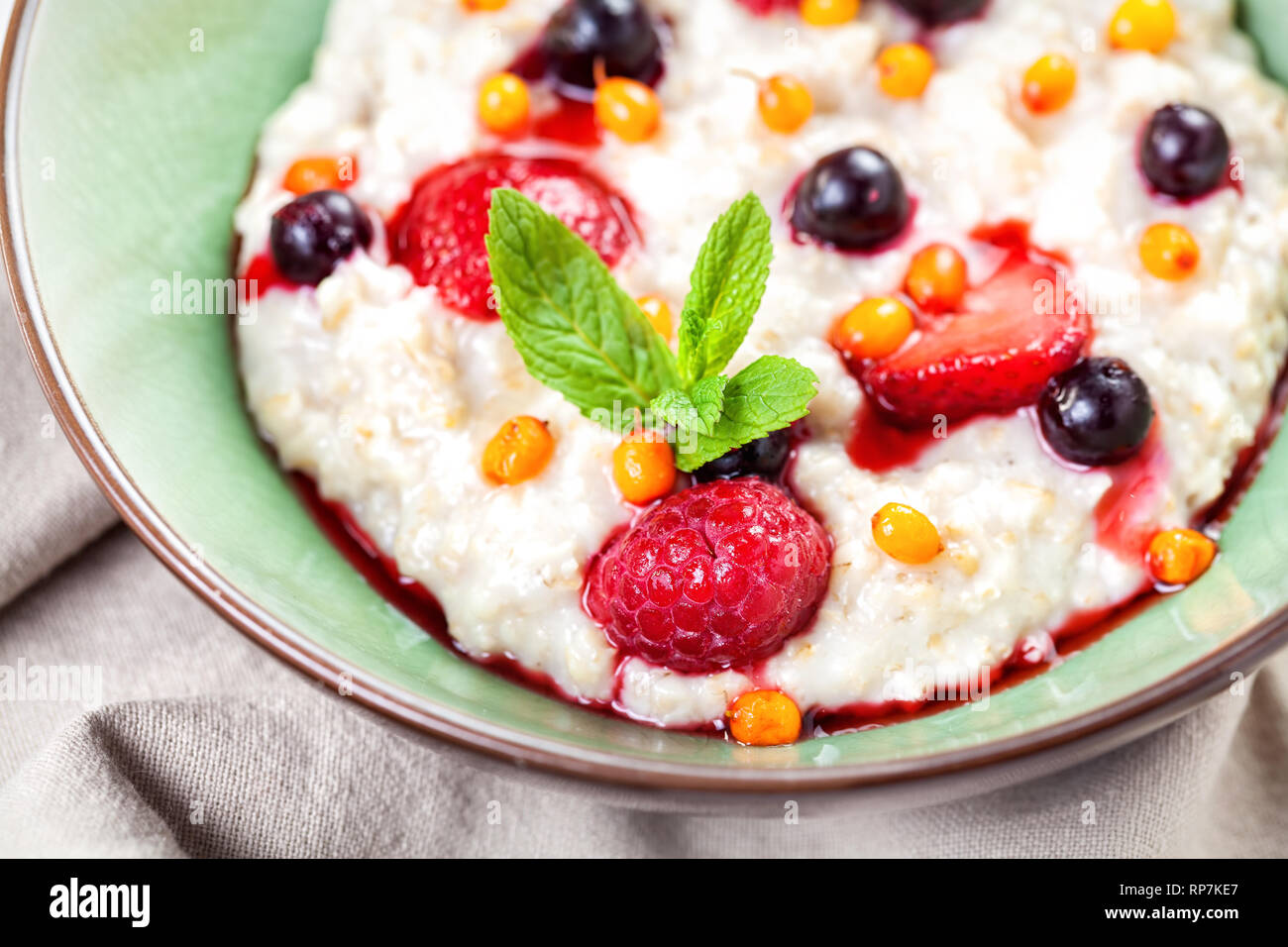 Porridge with fresh summer berries and mint close up in the restaurant ...