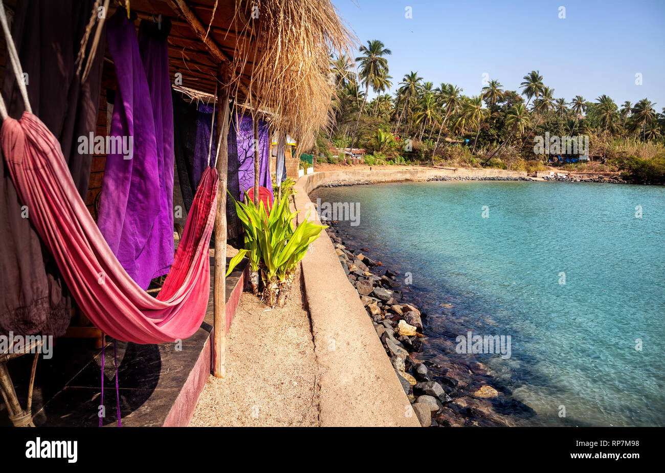 Resort with hammock near lagoon in sunny day at tropical Palolem beach ...