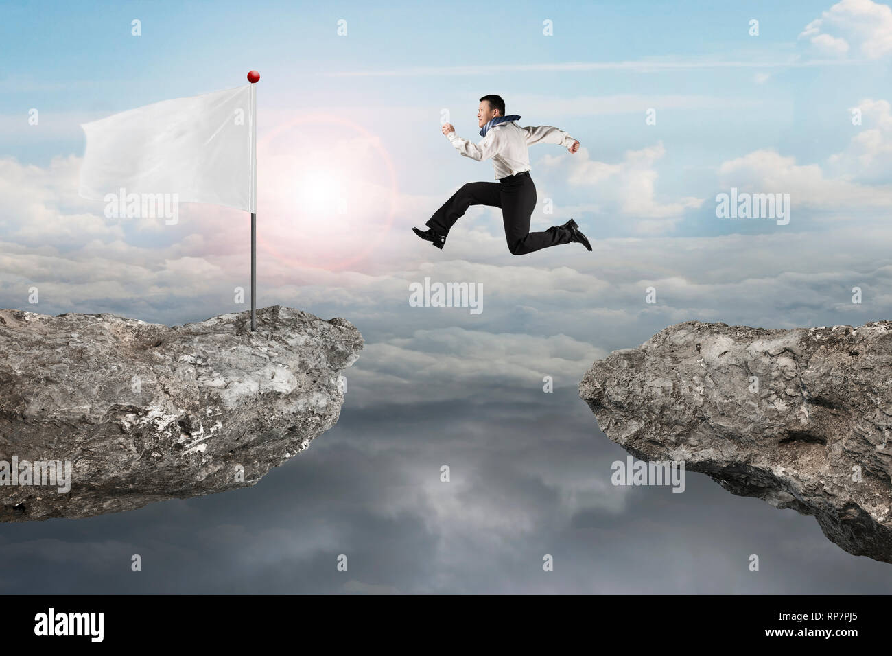 Man jumping on cliff with blank white flag and natural sunlight ...