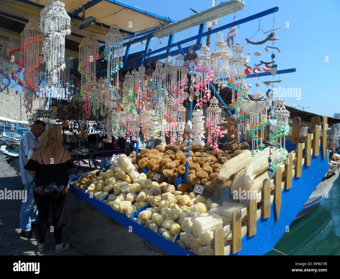 Tourists buying seashell wind chimes and sea sponge from a floating ...