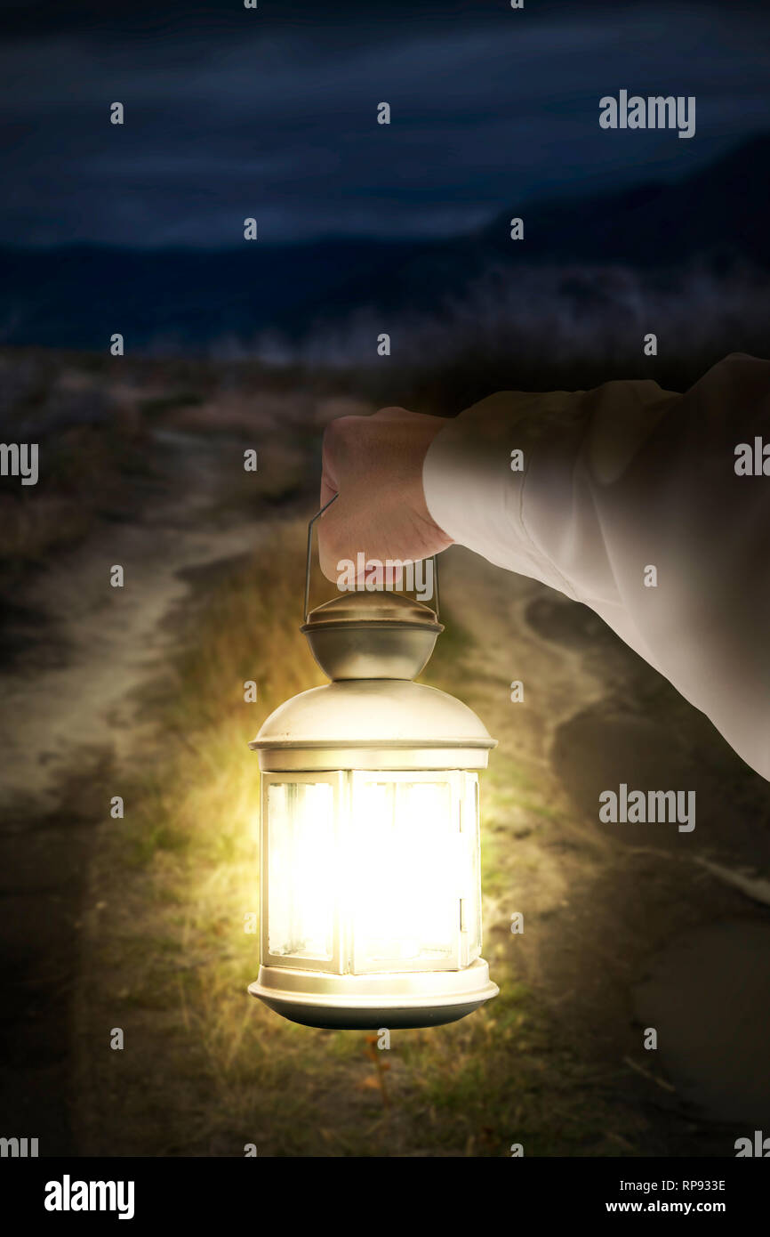 Right hand holding light illuminating dark road at night background ...
