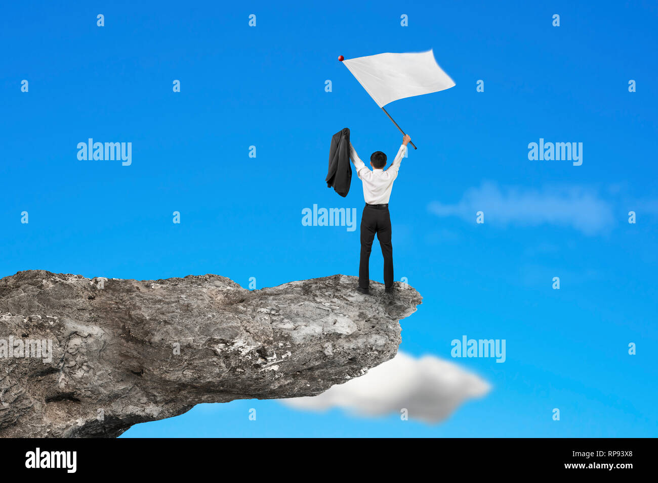 A businessman cheering on cliff waving blank white flag with natural ...