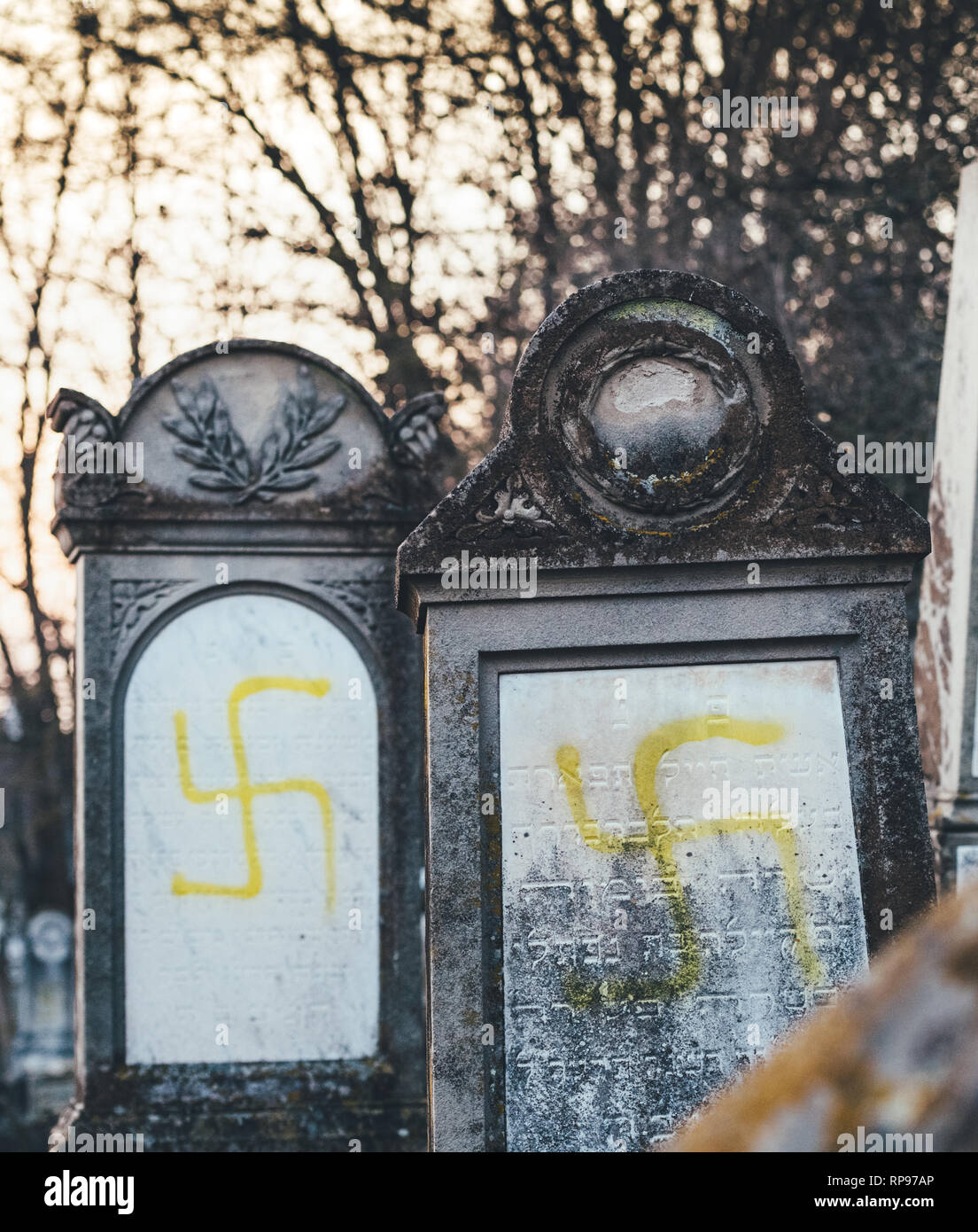 Vertical image of vandalised graves with nazi symbols in yellow spray ...