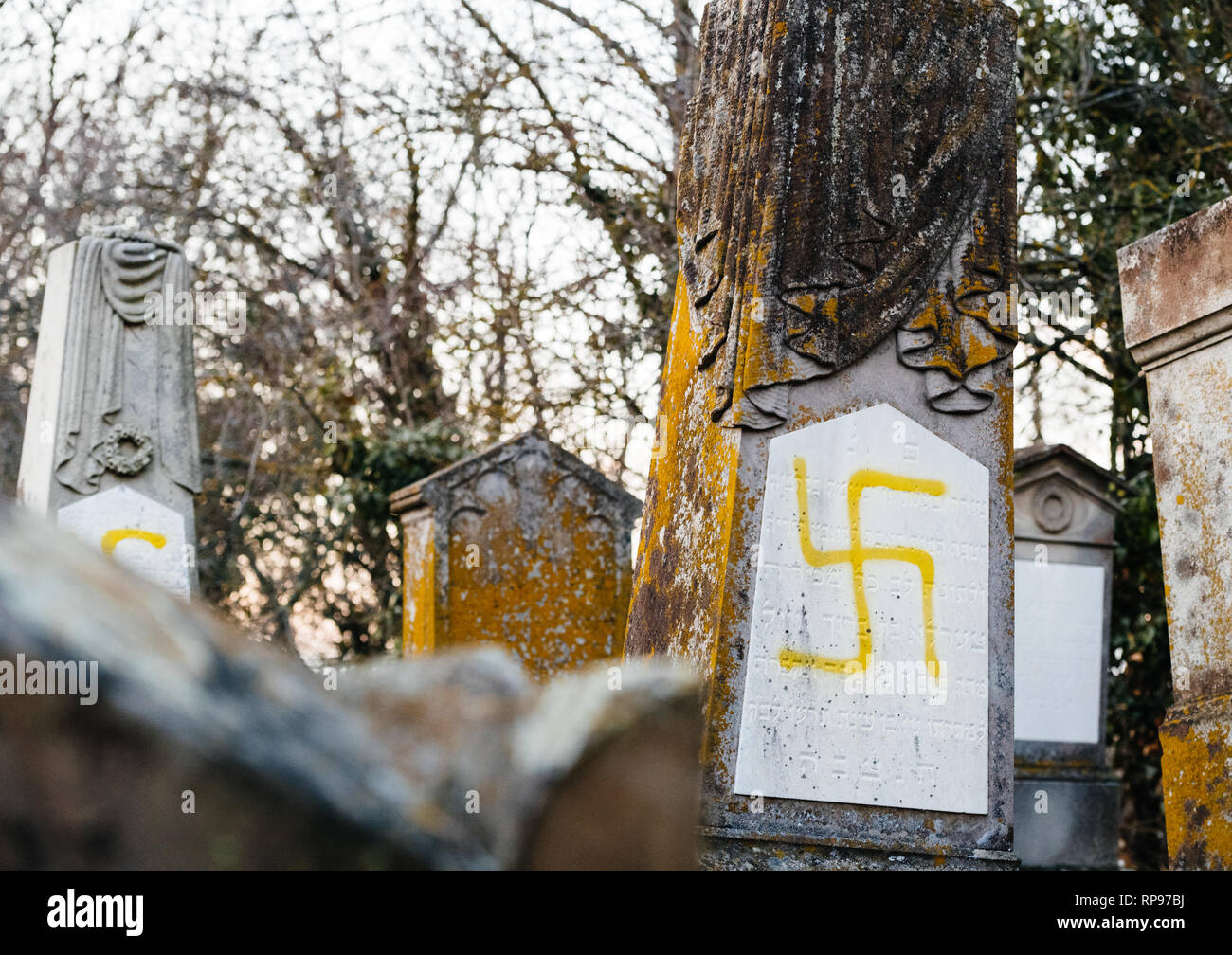 Low angle view of vandalised graves with nazi symbols in yellow spray ...