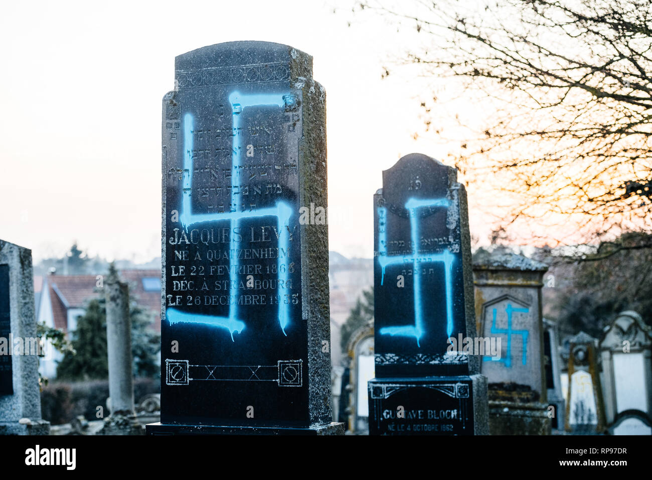 Low angle view of vandalised graves in with nazi symbols in blue spray ...