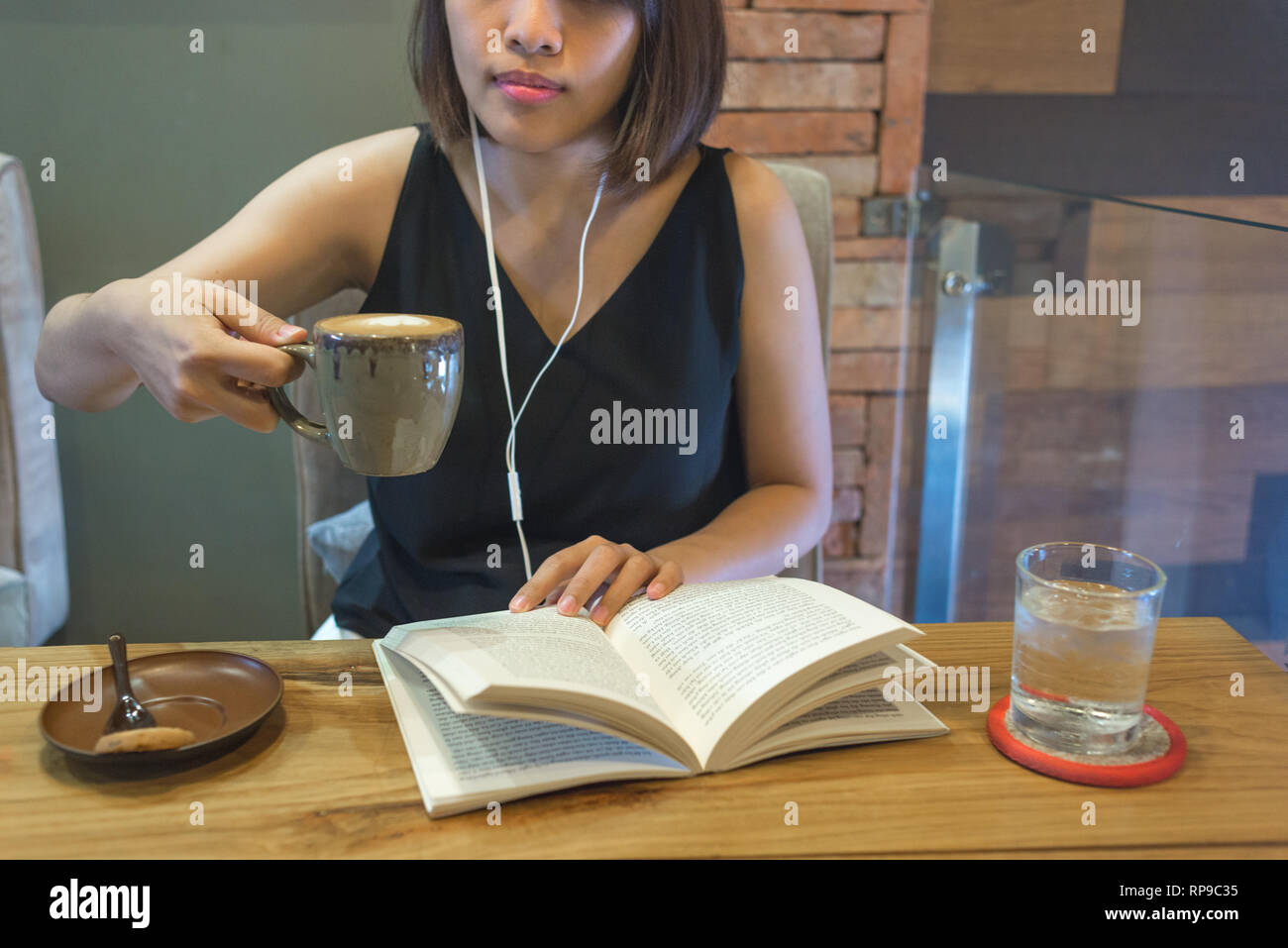 Young girl drinking coffee and reading book Stock Photo - Alamy