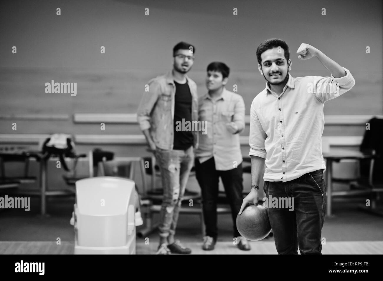 South asian man in jeans shirt standing at bowling alley with ball on ...