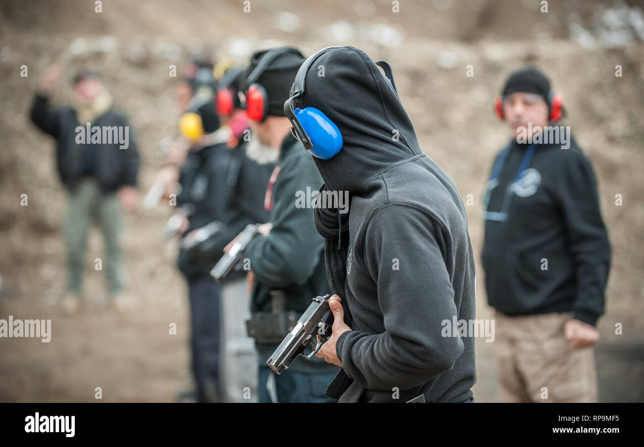 Large group of students with two instructors practice gun shooting on ...