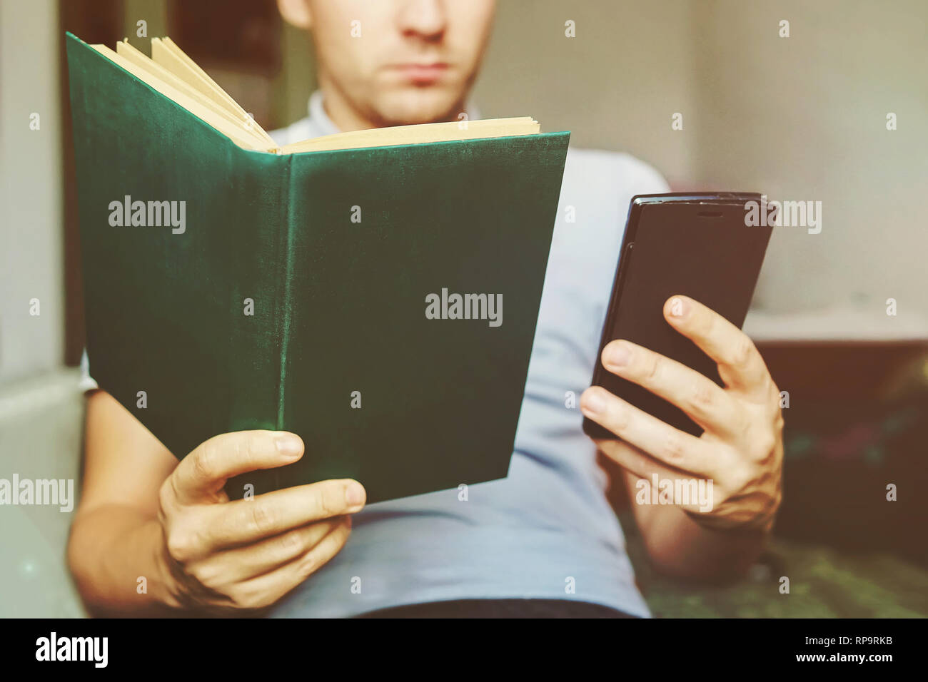 The guy reads the book. A man holds in one hand, smartphone in the ...