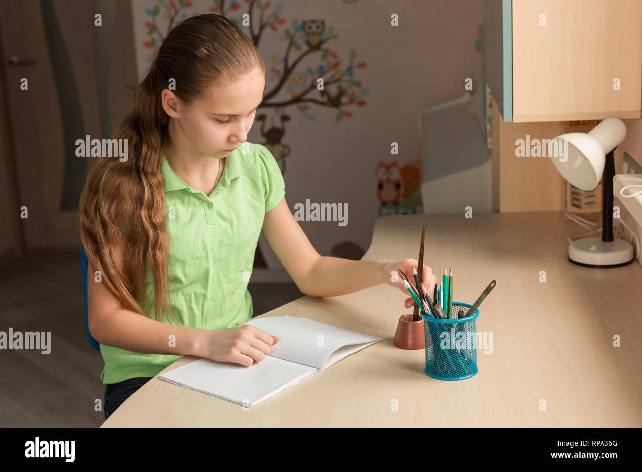 Cute little girl left-handed writing her homework at the table Stock ...