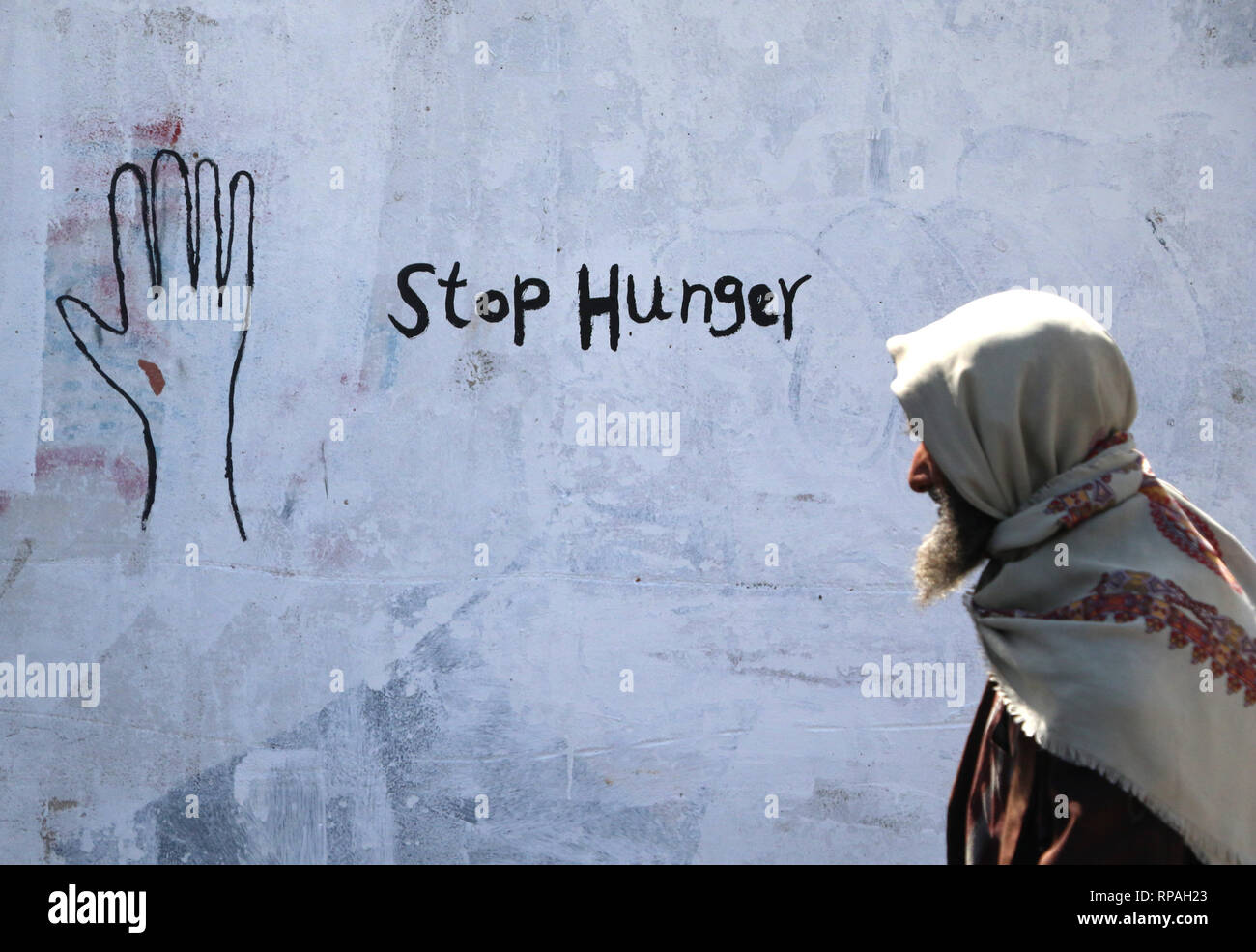 Sanaa, Yemen. 21st Feb, 2019. A Yemeni elderly man walks by graffiti ...