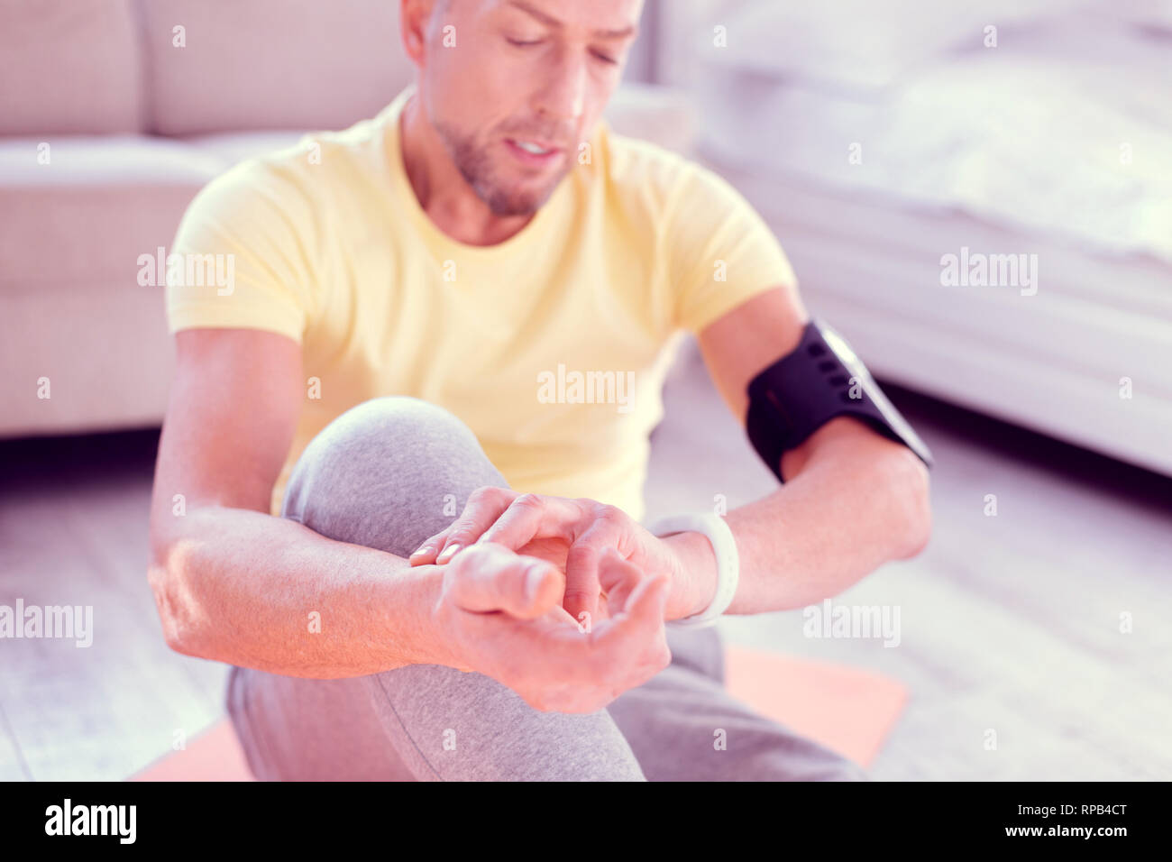 Bearded man caring about his health checking his pulse after exercises ...