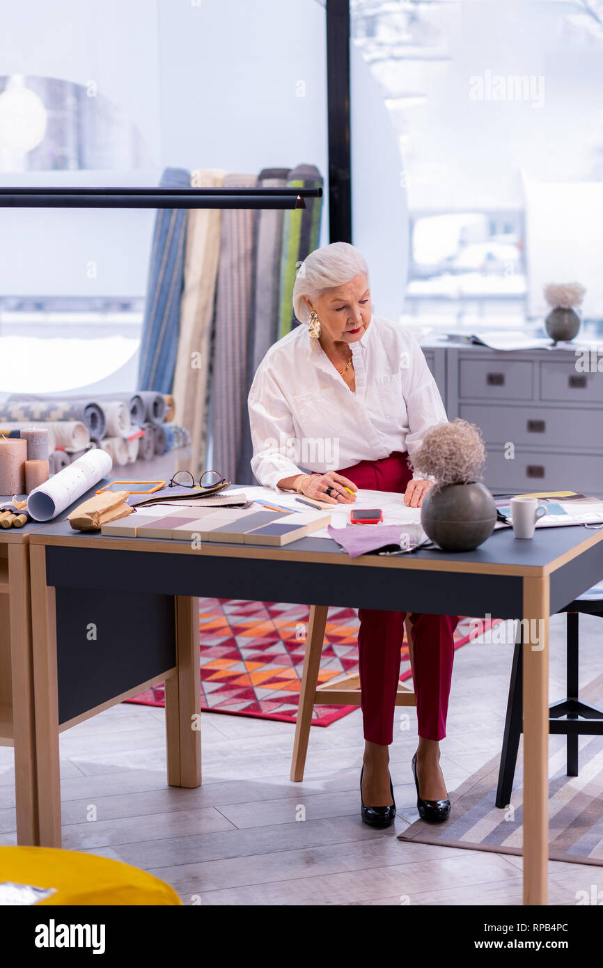 Charming silver-haired aging executive working at the table in office ...