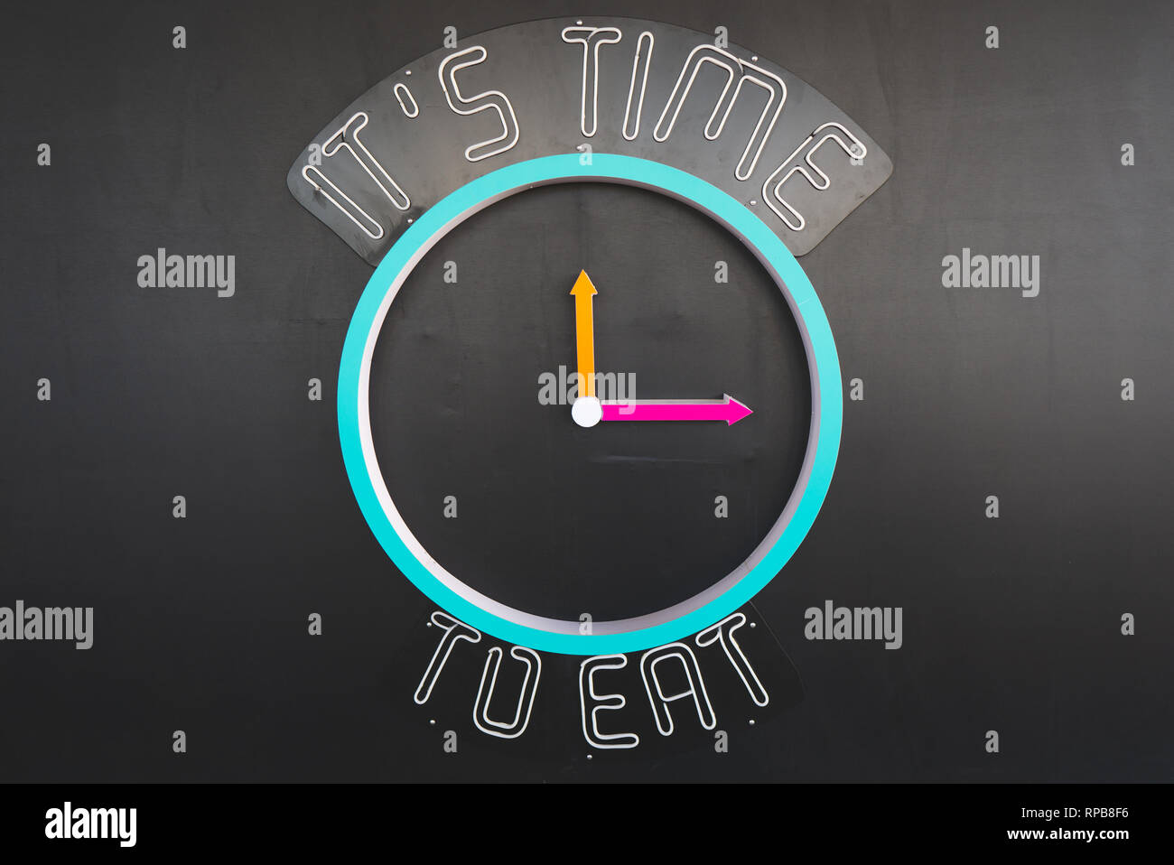 Neon concept clock sign showing "Eat Time". Maket clock on black wall ...