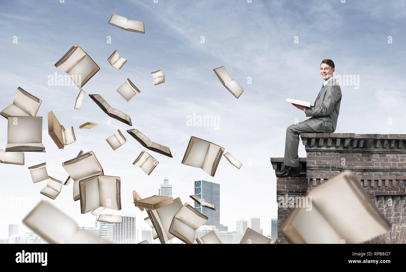 Man on roof reading book and many of them flying in air Stock Photo - Alamy