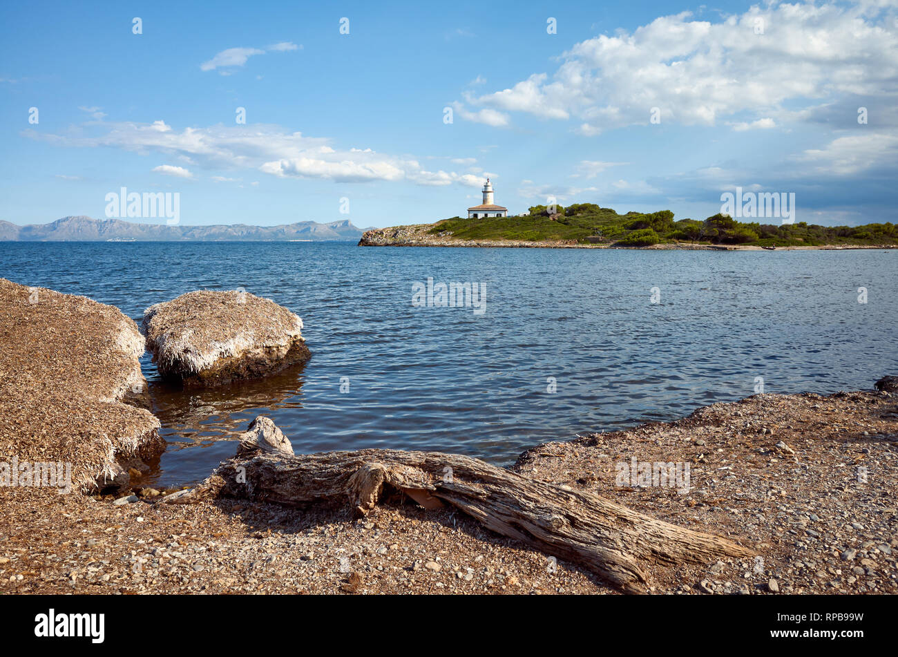 Beach with Alcanada Lighthouse (Faro de Alcanada) in distance, Mallorca ...