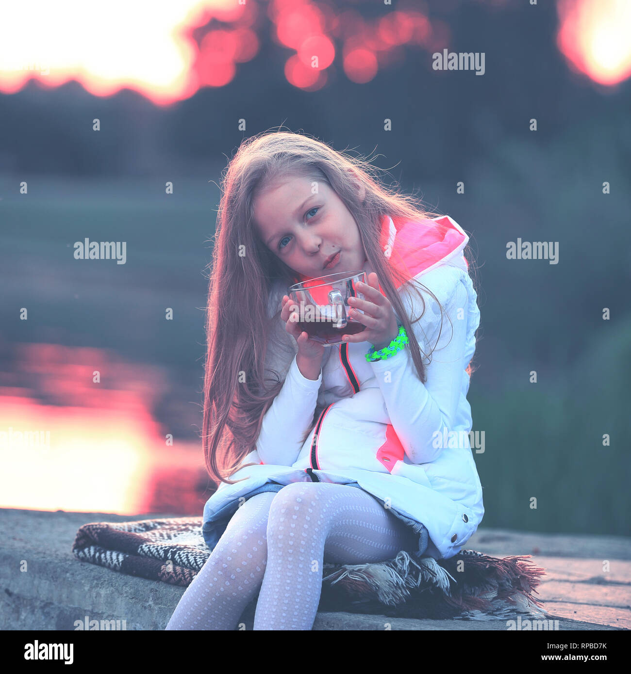 cute little girl with a Cup of tea sitting on a bench in the coo Stock ...