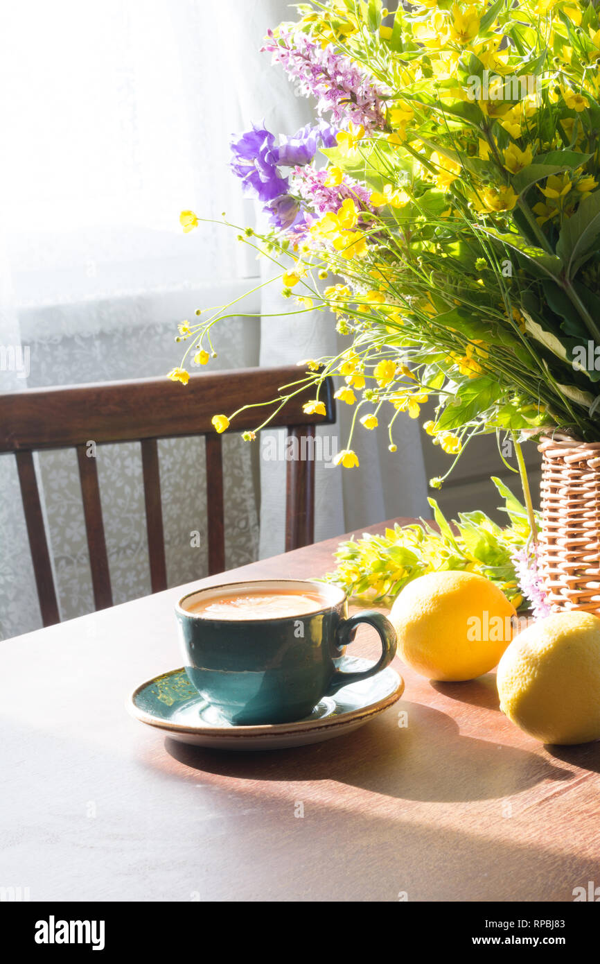 Morning with fresh cup of tea and wild flowers in basket. Rustic ...