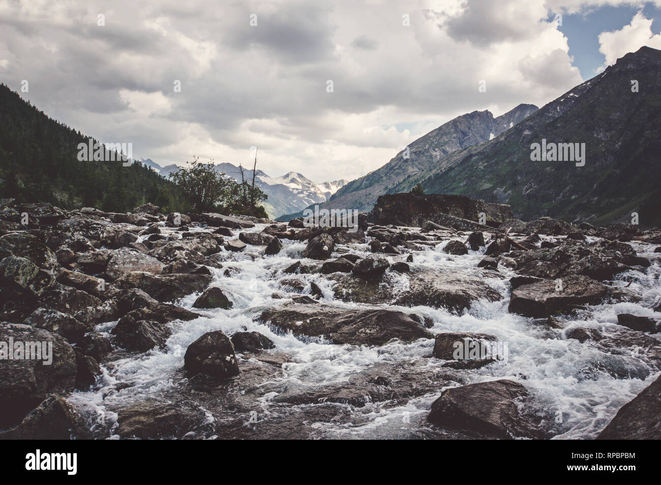 Clear river with rocks leads towards mountains. The river flows into ...