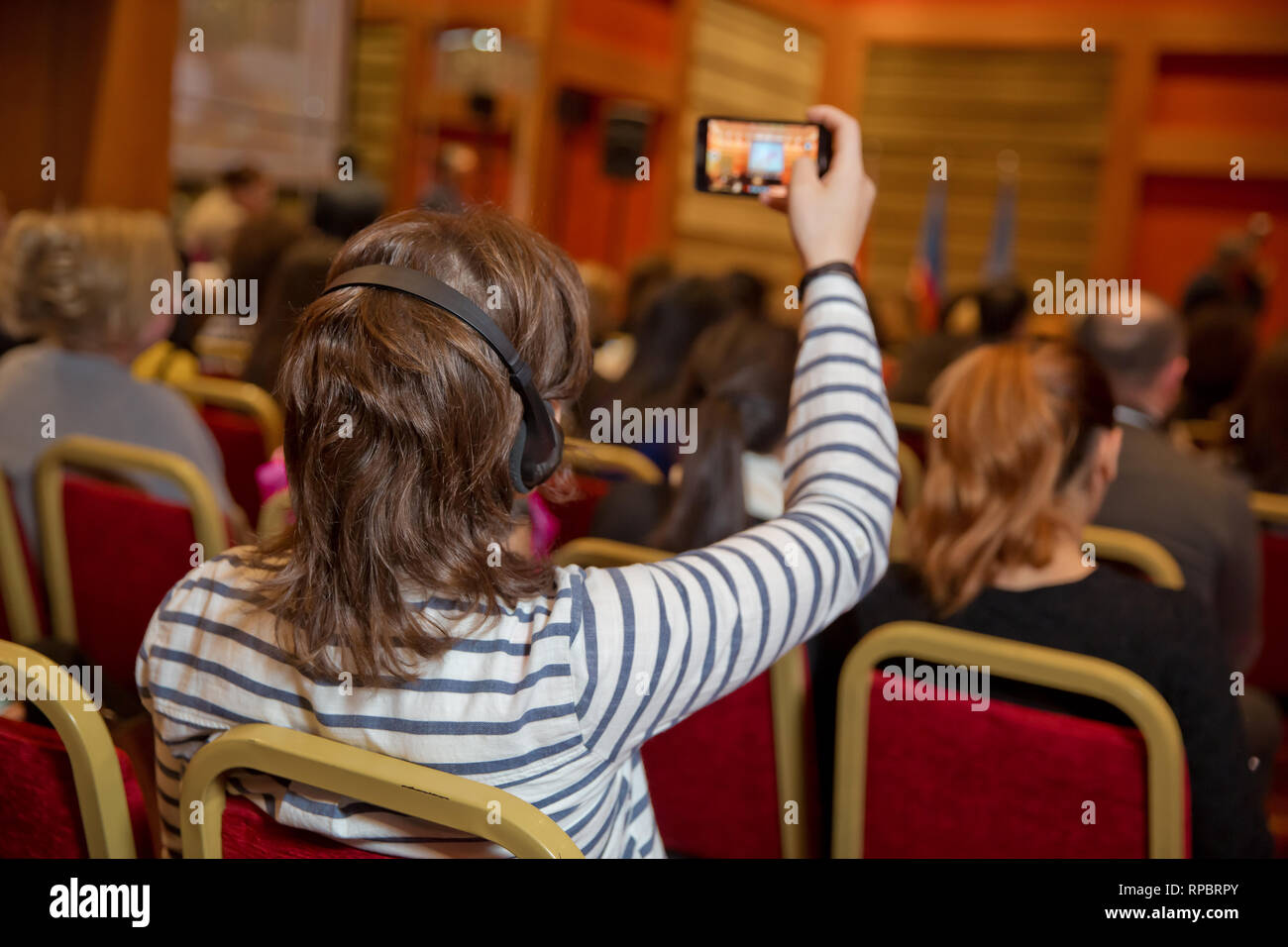 Man with headset at the conference . The audience wearing head phone ...