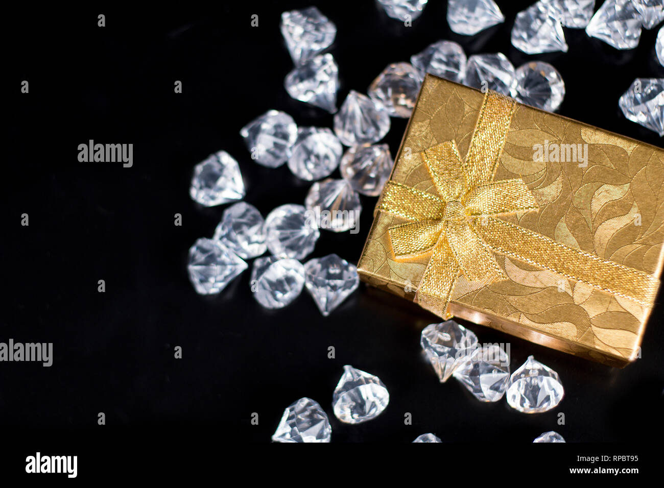 Golden jewellery box with shiny diamonds on a black glossy background ...