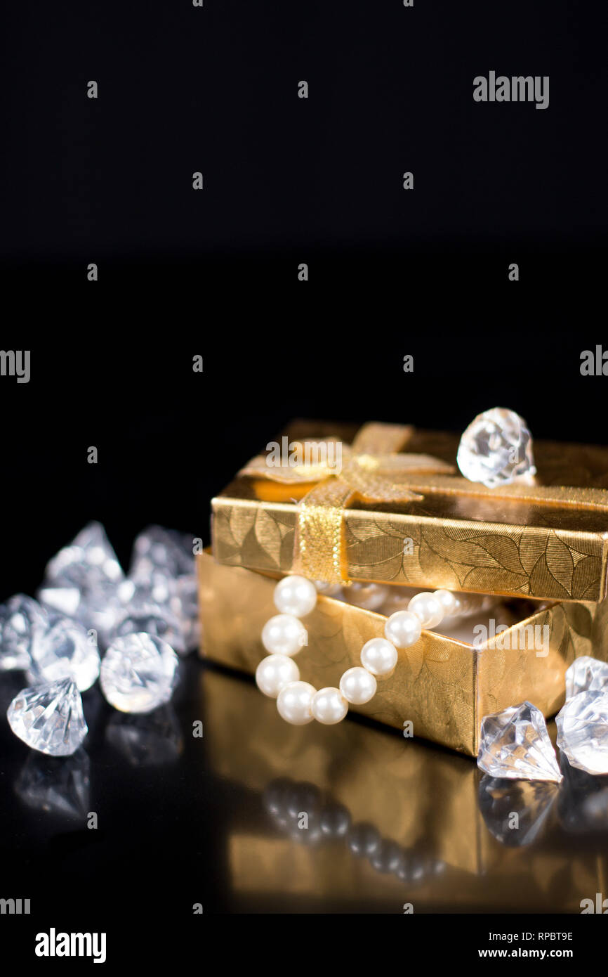 Golden jewellery box with shiny pearls on a black glossy background ...