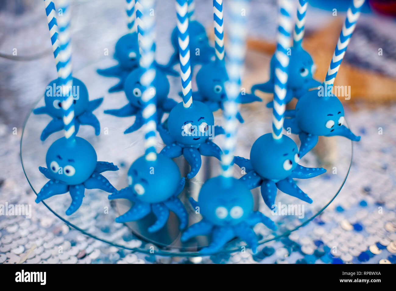 Blue cake pops funny octopuses shared on the glass round plate. Summer ...