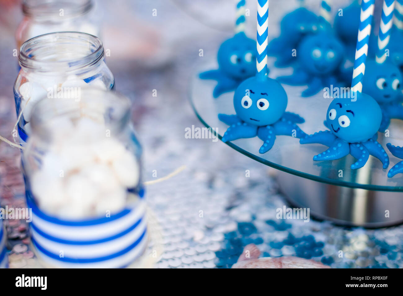 Blue cake pops funny octopuses shared on the glass round plate and jars ...
