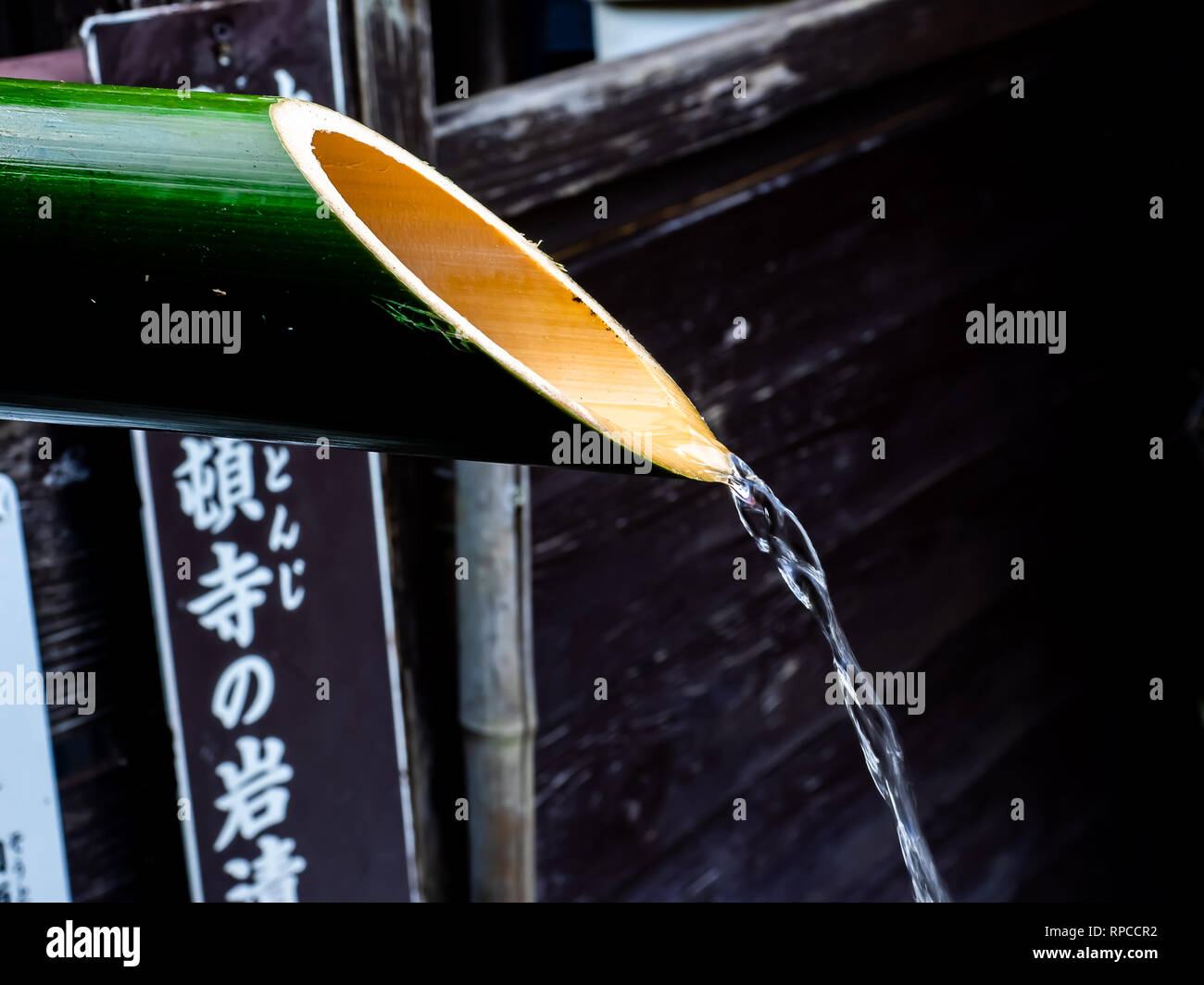 A bamboo pipe pours overflow water out of a Japanese hot spring bath on ...