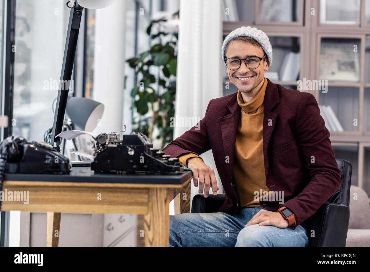 Well-groomed nifty smiling gentleman sitting at desk with typewriters ...