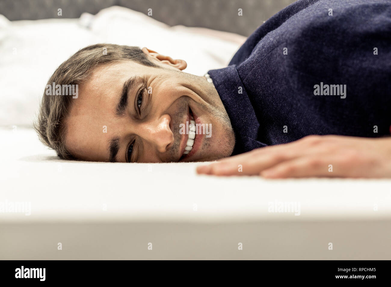 Portrait of smiling male face lying on white bed sheets Stock Photo - Alamy